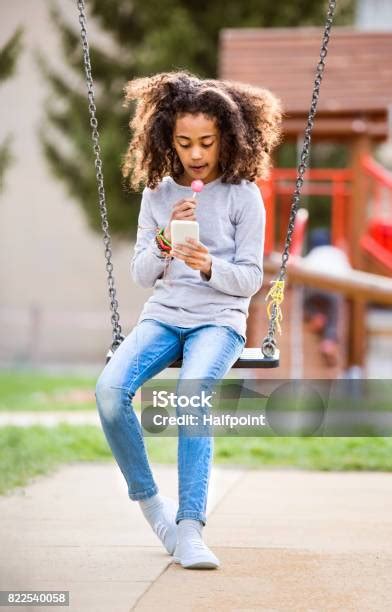 스마트 휴대 전화 문자 메시지와 함께 스윙에 아프리카계 미국인 여자 T 셔츠에 대한 스톡 사진 및 기타 이미지 T 셔츠 긴팔 갈색 머리 Istock