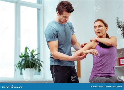 Serious Male Masseur Looking At His Patients Shoulder Stock Photo Image Of Healthcare Patient