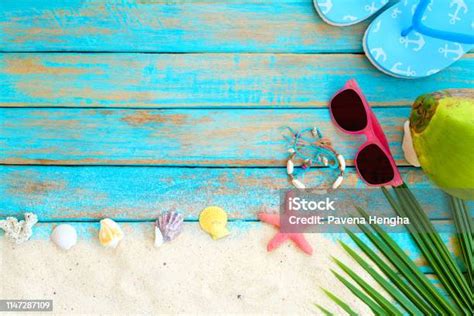 슬리퍼 코코넛 선글라스 코코넛 잎 불가사리 조개 껍질 산호 및 파란색 나무 바탕에 조개의 팔찌와 함께 해변 모래의 평면도