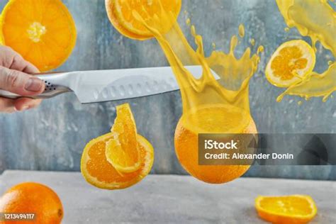 갓 자른 오렌지 부양 칼이 오렌지를 자른다 오렌지는 다른 방향에서 주스와 주스 흐름을 뿌린다 파란색 배경에 오렌지의 비행 조각 감귤류 과일에 대한 스톡 사진 및 기타 이미지