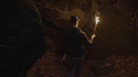 Man Holding A Burning Torchlight Exploring Forest Cave Landscape In Dark Night 42651399 Stock