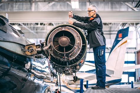 항공기 격납고에서 유지 보수 하는 동안 비행기에 작은 제트 엔진의 일부를 Unscrewing 고위 여성 비행기 엔지니어 노동자 계급에 대한 스톡 사진 및 기타 이미지
