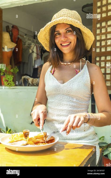 Young Woman Wearing A Straw Hat Enjoying A Delicious Breakfast At An