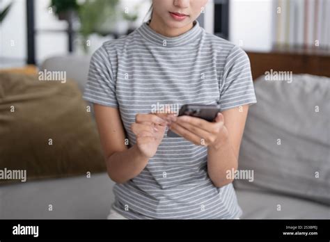 Asian Woman Controlling Smart Home Mobile Phone With Smart Home App In