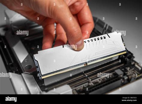 A Person Is Installing A White Ddr Memory Module Into A Desktop
