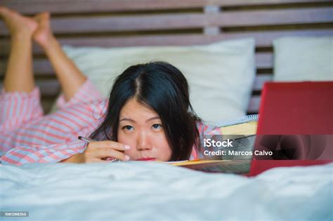 젊은 좌절과 피곤 아시아 일본 대학 학생 여자 지 루 느낌 및 생각 하 고 침대에 누워 집 침실에 잠겨있는 노트북 컴퓨터와 함께 공부 하는 게으른 준비 시험 걱정하는에 대한