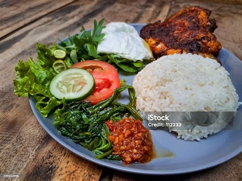 닭 허벅지 필레 줄기 흰 쌀 삼발 또는 칠리 소스 양배추 양상추 시금치 오이 토마토 라임 케니키르 잎을 곁들인 맛있는 나시 아얌 범부 루작 또는 루작 시즈닝 치킨 음식 메뉴