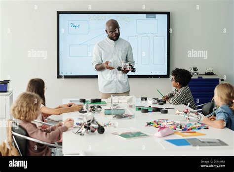 Confident Male Teacher Of Robotics Explaining Intercultural Elementary School Learners How To