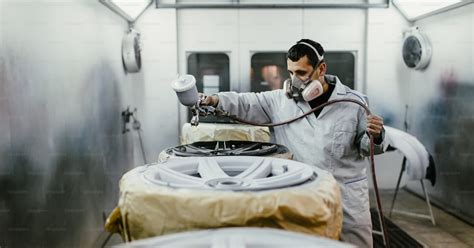 보호복을 입고 스프레이 압축기를 사용하여 자동차 부품을 칠하는 마스크를 쓴 남자 선택적 초점 사진 Unsplash의