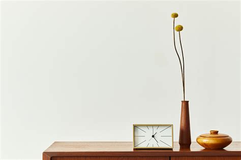 세련된 티크 컴모드 디자인 장식 식물 시계 복사 공간 및 우아한 개인 액세서리가있는 스칸디나비아 인테리어 고전적인 집에 있는