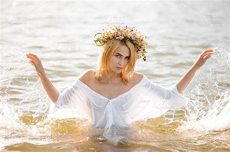 穿着白色湿衬衫戴着花圈站在水里的女孩