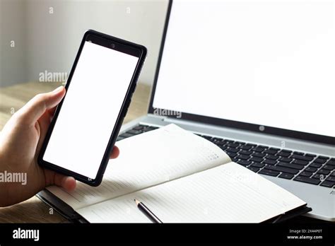 Blank White Screens Of Mobile Phone And Laptop Man Holding Phone In Front Of Laptop At The