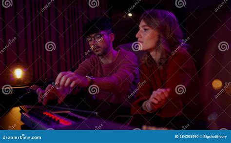A Music Male Producer And A Female Vocalist Making Music Together Using A Console And Computer