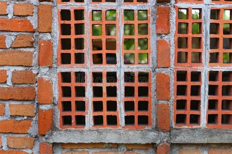 red clay bricks form a structured wall with small square openings stock