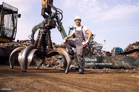 고철 부품을 들어 올리는 데 사용되는 발톱 부착장치가 있는 유압 산업용 기계 옆에 서 있는 폐차장 작업자의 초상화 갈고리 발톱에 대한 스톡 사진 및 기타 이미지 Istock