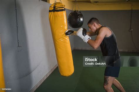 권투 글러브를 손에 끼고 체육관에서 펀칭백을 날리는 강한 남자 권투 선수 건강관리와 의술에 대한 스톡 사진 및 기타 이미지