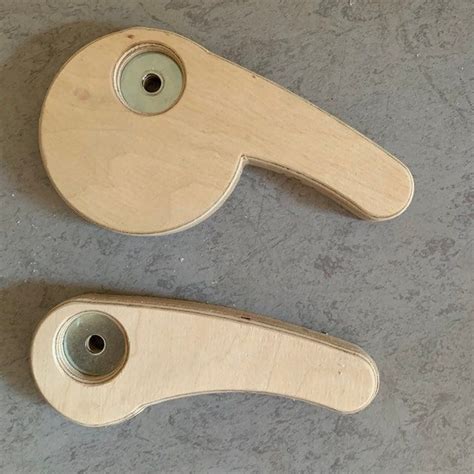 Two Wooden Handles With Holes In Them On A Gray Surface Next To Another One That Is Made Out Of