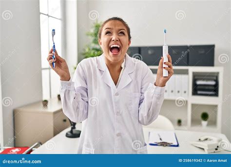Young Hispanic Dentist Woman Holding Ordinary Toothbrush And Electric