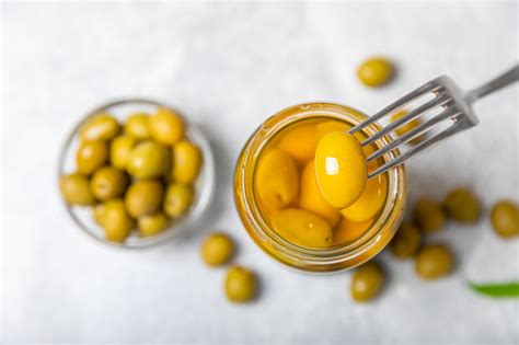 콘크리트 배경에 유리병에 담긴 올리브 항아리에 움푹 들어간 그린 올리브 유리병에 절인 올리브 나무 배경에 마리나드 올리브 텍스트를 위한 공간입니다 복사를 위한 공간 비건