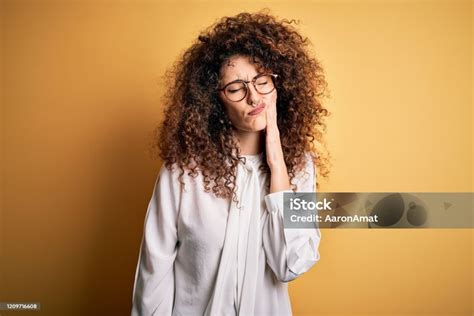 곱슬 머리와 피어싱 셔츠와 안경 때문에 치아에 치통이나 치과 질환의 고통스러운 표정으로 손을 만지는 입을 관통하는 젊은 아름다운 갈색 머리 여자 치과 의사 건강관리와 의술에