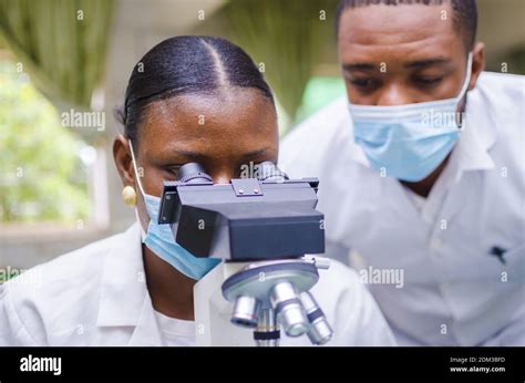 A Young African Male And Female Scientists Looking Through A Microscope In The Laboratory Stock