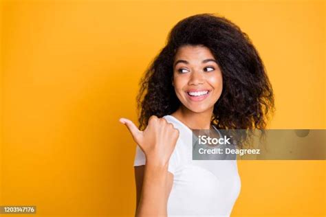 사진 의 쾌활한 긍정적 인 좋은 예쁜 여자 친구는 흰색 티셔츠 고립 선명한 색상 배경에 엄지 손가락 으로 이빨을 미소와 빈 공간을 가리키는 노란색 배경에 대한 스톡 사진 및