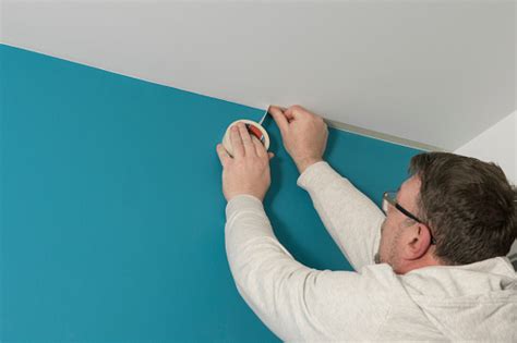 벽을 다른 색으로 칠하기 전에 흰색 천장에 마스킹 테이프를 붙입니다 마스킹 테이프에 대한 스톡 사진 및 기타 이미지 마스킹