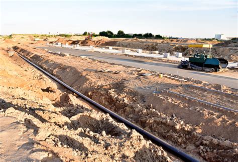 도로를 아스팔트하고 건설 현장에 하수도 파이프를 배치 도로 작업 중 아스팔트 파버 기계 포장 작업을위한 도로 기계 사이트 물 메인의 난방 파이프 및 폭풍 시스템 건설 산업에