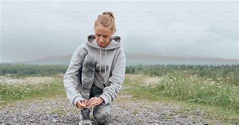 신발 끈을 묶고 야외에서 운동을 준비하는 중년 여성 그녀는 경치가 좋은 시골 길에 있습니다 사진 Unsplash의 구두 이미지