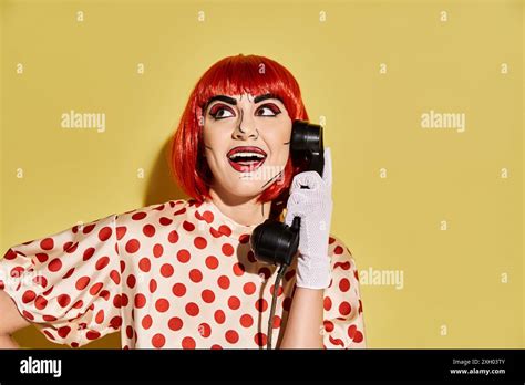 A Vibrant Redhead Woman In Comic Inspired Makeup Chats On A Phone Against A Bright Yellow