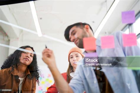비즈니스 전문가는 스티커 메모로 덮인 유리 벽을 사용하여 팀 회의 중에 프로세스를 간략하게 설명합니다 접착식 메모지에 대한 스톡 사진 및 기타 이미지 Istock