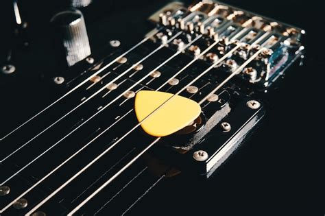 Premium Photo Pick Between The Strings On The Soundboard Of A Black Electric Guitar Closeup