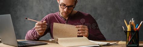 The Man Sitting At The Table While Flipping Through Papers In The