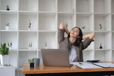 A Businesswoman Stretches Lazily On Her Desk For Relaxation While Working In The Office Stock