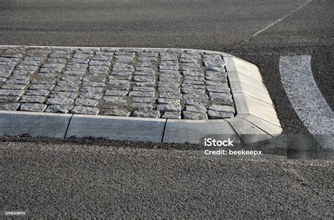 중앙에 가까운 압연 틀에 회색 화강암 큐브의 포장의 원형 원 한가운데꽃과 풀이 있는 교통 허브인 콘크리트 연석이 뒤섞인 다 다년생 화단 0명에 대한 스톡 사진 및 기타