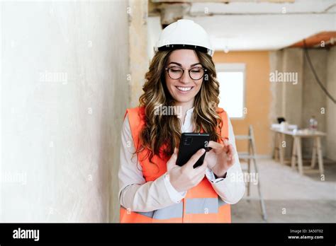 Professional Architect Woman In Construction Site Using Mobile Phone And Blueprintshome