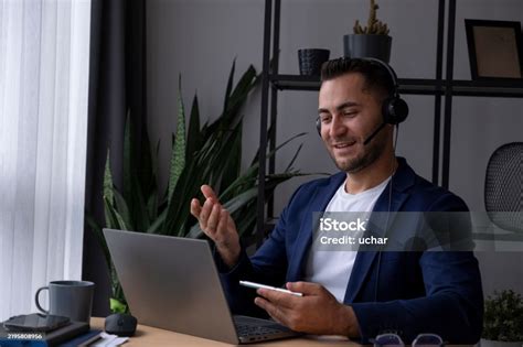 헤드셋을 착용한 젊은 사업가가 자택 사무실에서 노트북으로 화상 통화를 하고 있습니다 20 29세에 대한 스톡 사진 및 기타 이미지 20 29세 30 34세 Brand