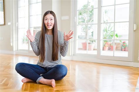 집에서 바닥에 맨발로 앉아 있는 아름다운 아시아 여성은 미친 듯이 미친 듯이 외치고 공격적인 표정과 팔을 들고 고함을 쳤습니다 좌절 개념입니다 가정 생활에 대한 스톡 사진