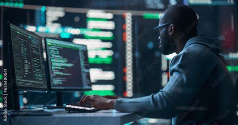 black male programmer working in monitoring room surrounded by big