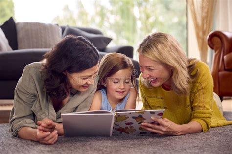 Familia Del Mismo Sexo Con Dos Madres E Hija Tendidas En El Piso Leyendo El Libro Juntos En Casa