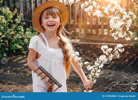 Een Lachend Boerenmeisje In Een Hoed In De Tuin Maakt Een Gras Voor Het Oogsten Van Bladeren In
