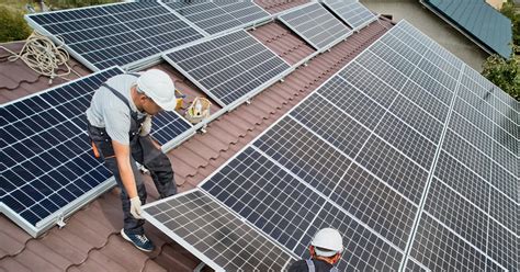 집 지붕에 태양광 모듈을 설치하는 남성 설치자 헬멧을 쓴 엔지니어들이 야외에서 태양 전지판 시스템을 구축합니다 대체 및 재생 가능 에너지의 개념입니다 조감도 사진