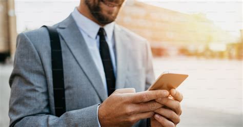 스마트폰을 들고 있는 사업가의 손을 클로즈업 통신 기술 개념입니다 따뜻한 백라이트 사진 Unsplash의 양복 이미지