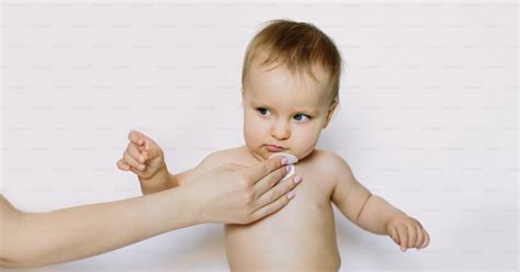 젊은 엄마는 흰색 배경에 물티슈로 아기 피부 몸과 얼굴을 조심스럽게 닦고 있습니다 컨셉 클리닝 와이프 순수하고 깨끗합니다 사진 Unsplash의 손가락 이미지