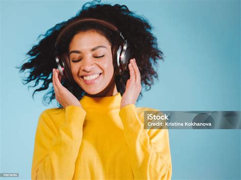 매력적인 아프리카 여자 춤 동작 머리 비행 헤드폰 입고 노란색 스웨터 블루 스튜디오 화려한 그림 유행 소녀 거리에 대한 스톡 사진 및 기타 이미지 Istock