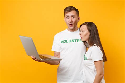 동료 몇 비문 녹색 흰색 티셔츠에 노란색 배경에 절연 입력 노트북 Pc 컴퓨터를 사용 하 여 자원 봉사 자발적인 무료 작업 지원 도움말 자선 총 팀워크 개념 T 셔츠에 대한