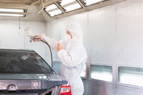 챔버에 있는 기계공 페인팅 자동차 스프레이 건과 에어 브러시를 사용하고 자동차를 칠하는 작업자 차고 페인팅 자동차 서비스 수리