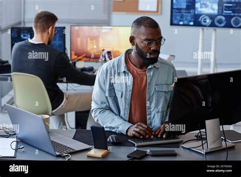 portrait of black man using computer while writing software code in