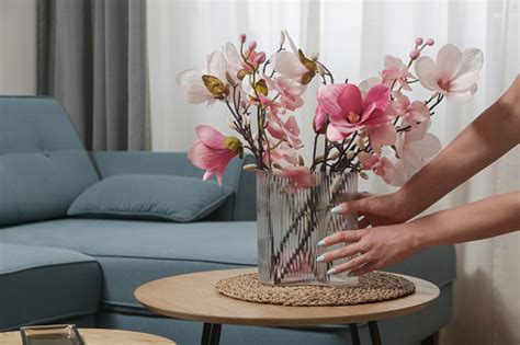 테이블에 꽃이 든 꽃병을 준비하는 여자 아파트에서 아늑함을 돌보는 주부 인테리어 장식 가정 및 주택 개량 개념 호화로움에 대한