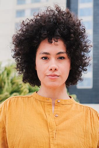 바깥에 서 있는 카메라를 바라보며 생각에 잠긴 젊은 성인 여성의 세로 개인 초상화 진지한 표정과 곱슬머리를 가진 자랑스러운 히스패닉 여성의 얼굴 사진 고민하는 성공한 여성